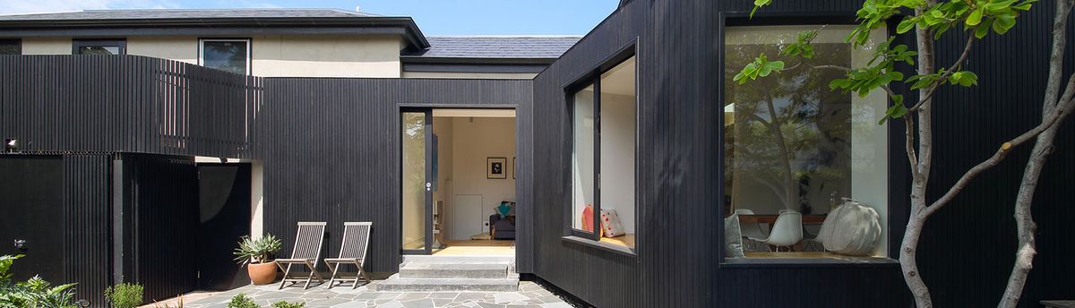 At Merton House a Curving Dark Timber Wall Creates the New Home's Edge